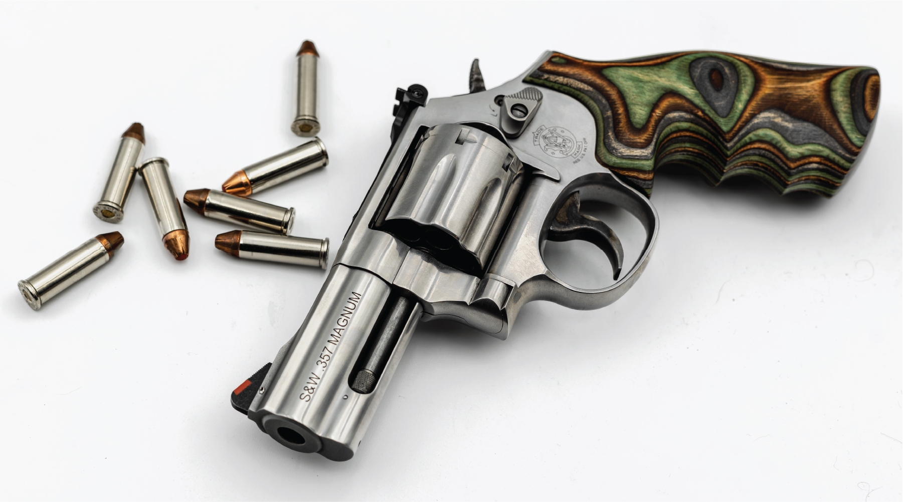 Revolver with a multicolored grip lying next to bullets